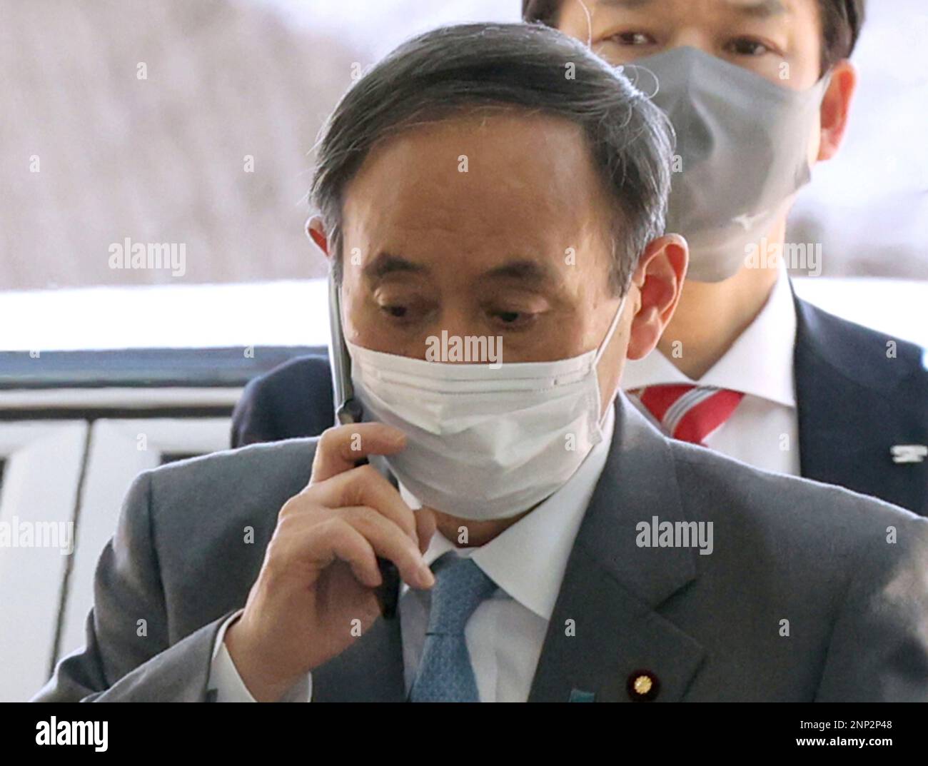 Japan's Prime Minister Yoshihide Suga holding a mobile arrives at Prime ...