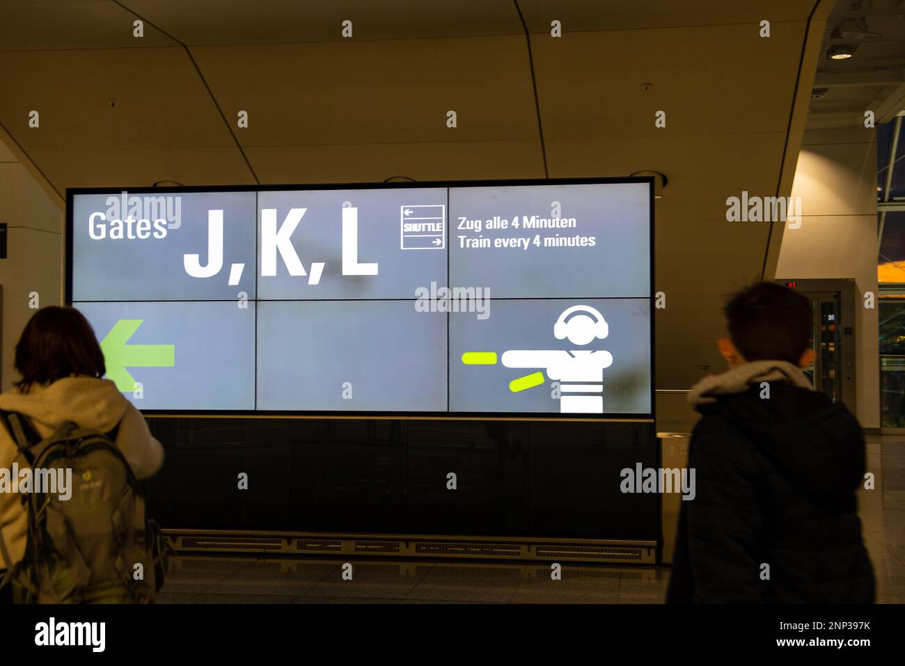 Two passengers walk by a sign in germany indicating the way to a ...