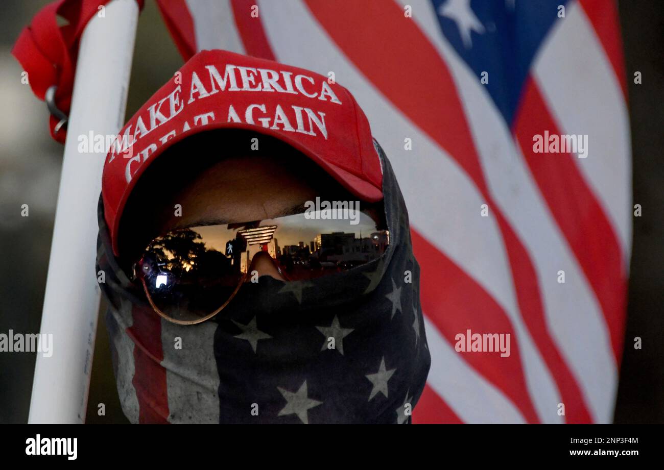 A man wearing a MAGA har and carrying a flag protests during a pro ...