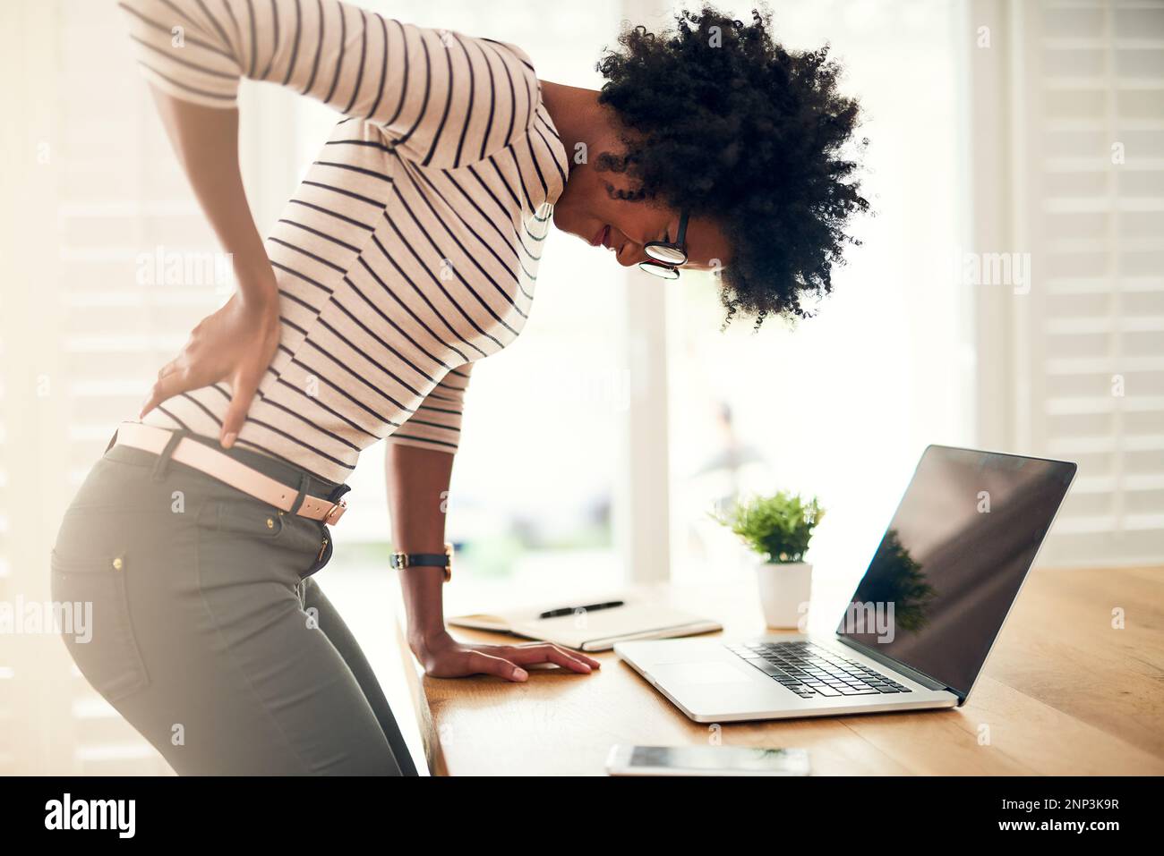 Poor posture can lead to back pain. a young woman holding her sore back ...
