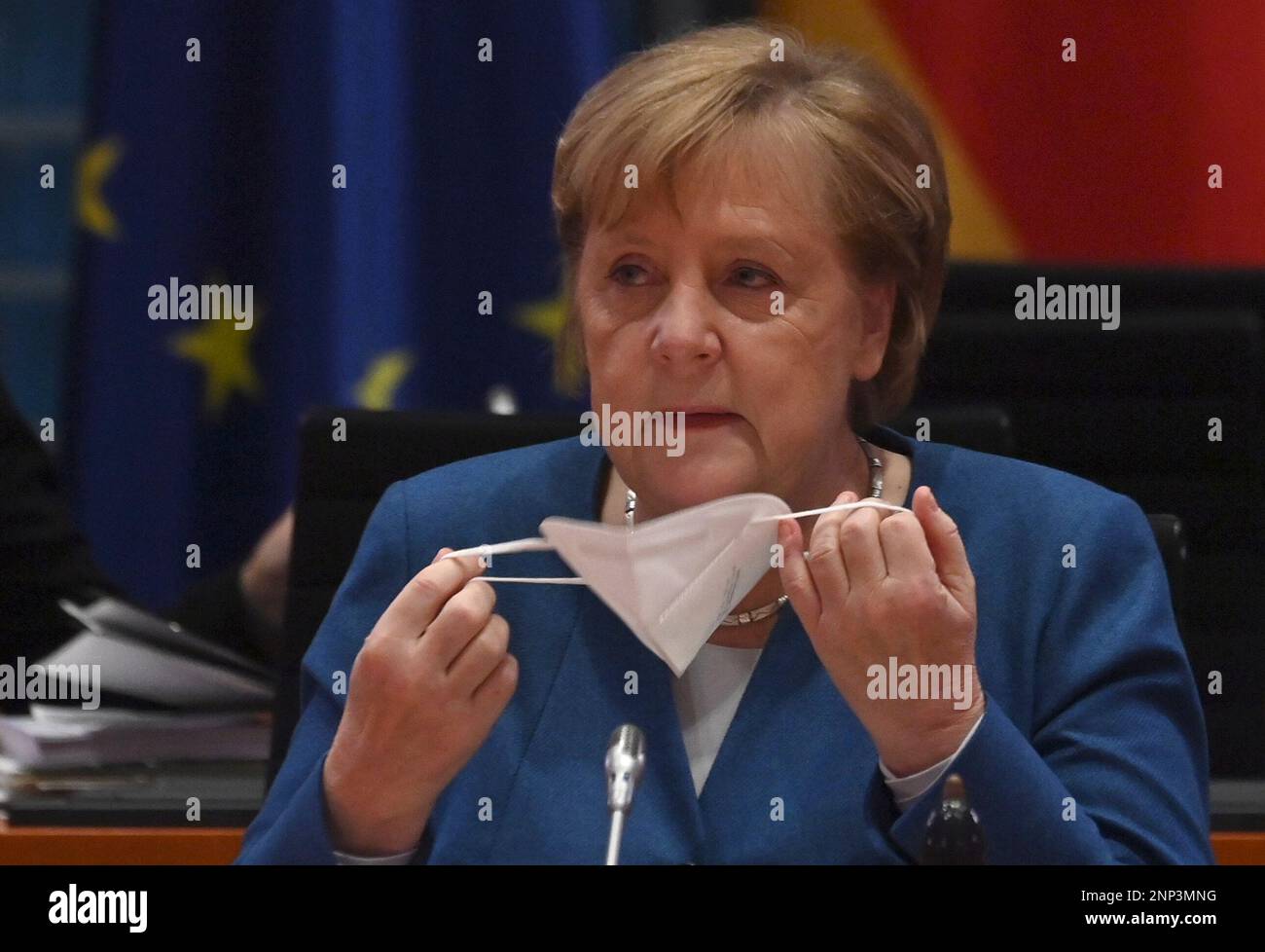 German Chancellor Angela Merkel takes off her face mask as she prepares ...