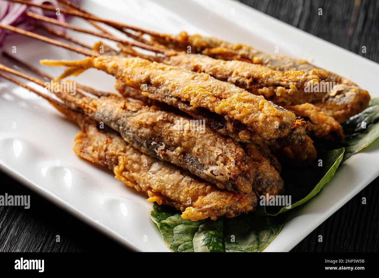 Portion of asian fried capelin skewers with onion Stock Photo - Alamy