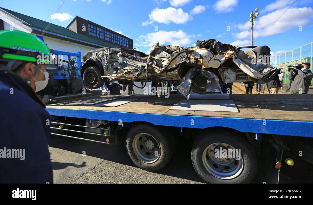 Workers bring a tsunami-damaged police patrol vehicle into the town's ...