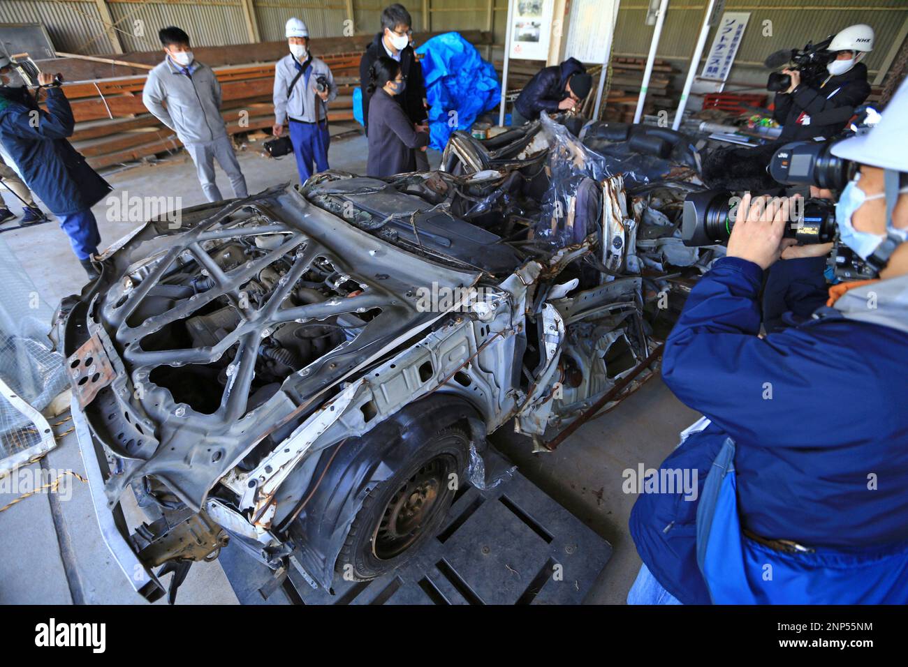 Workers bring a tsunami-damaged police patrol vehicle into the town's ...