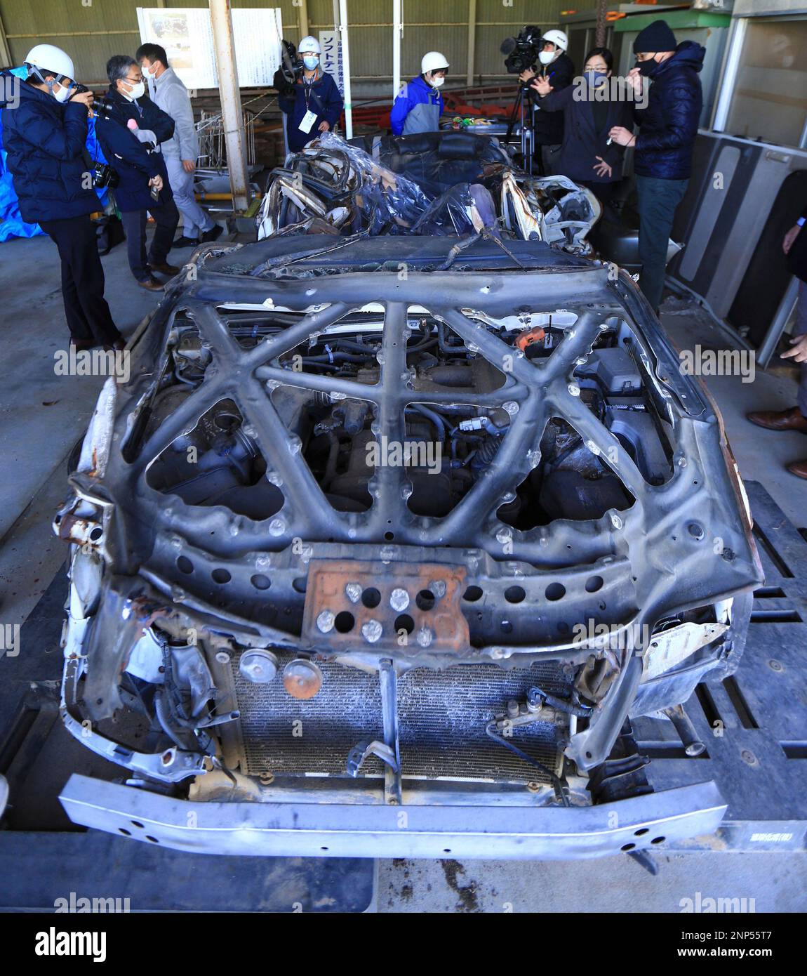 Workers bring a tsunami-damaged police patrol vehicle into the town's ...