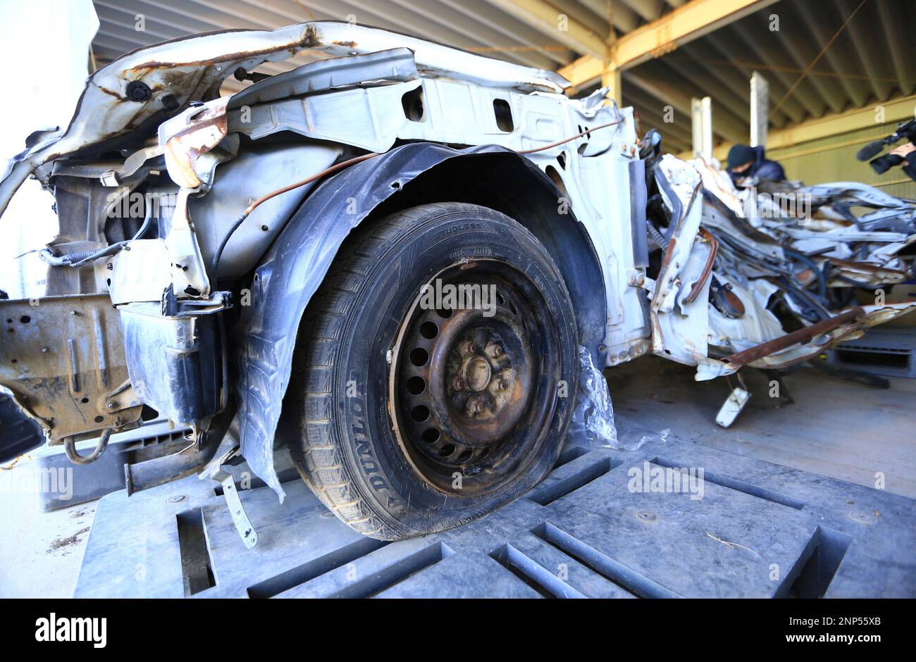 Workers bring a tsunami-damaged police patrol vehicle into the town's ...