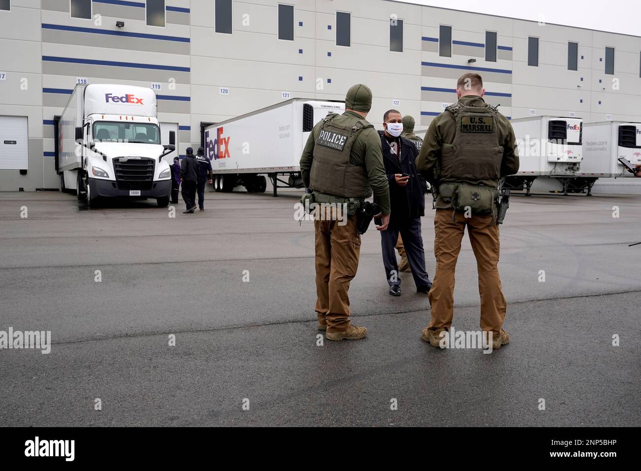 U.S. Marshalls stand near FedEx trucks parked at the loading dock ...