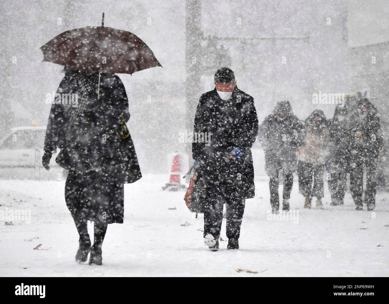 Commuters wearing masks are seen in snow due to a cold front in Sapporo ...