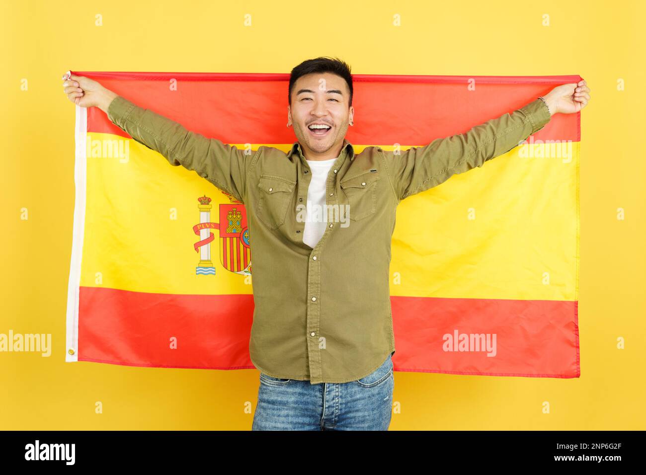 Chinese man smiling and raising a spanish national flag Stock Photo - Alamy