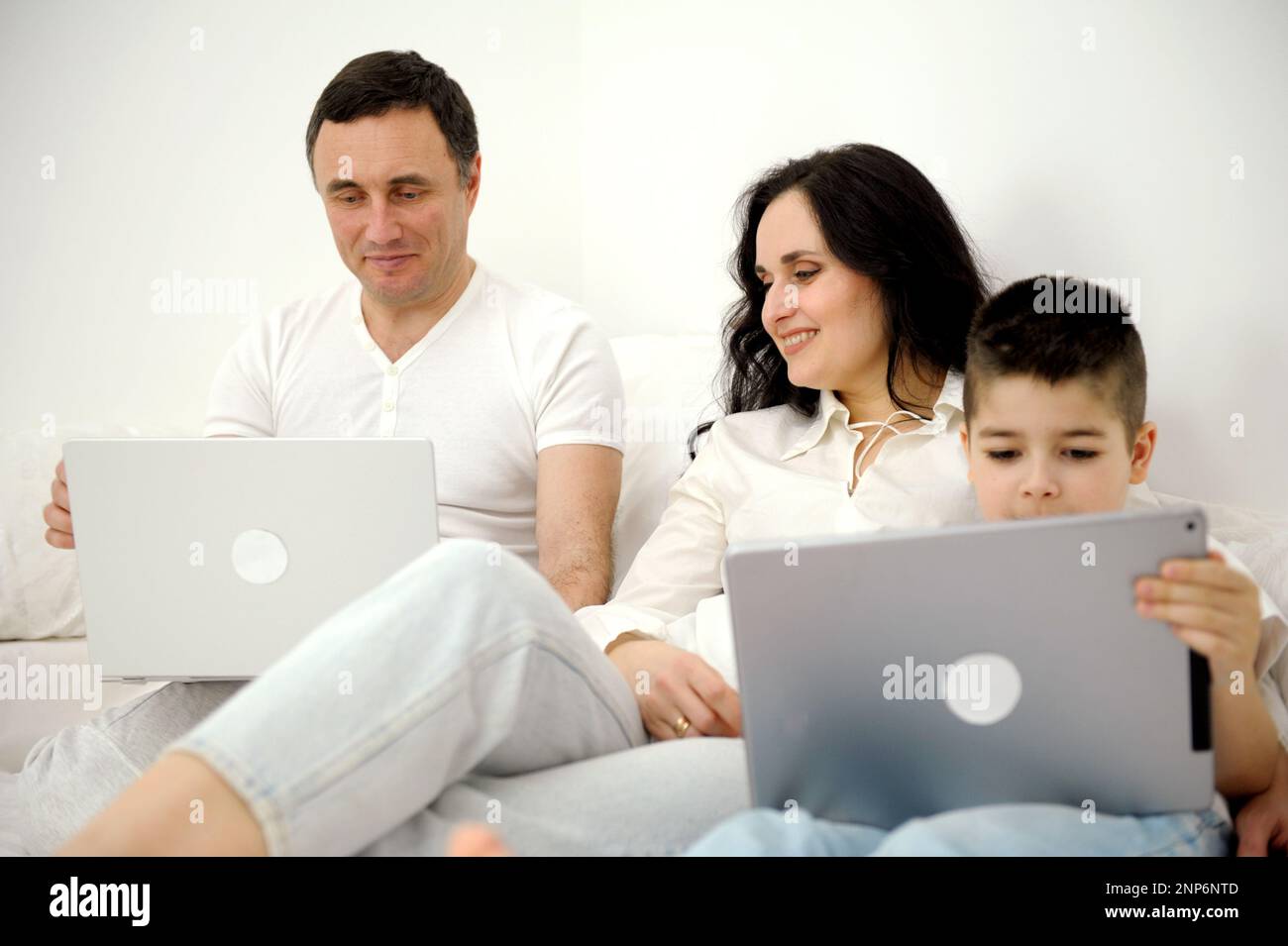 latest technology gadgets mom and son playing on tablet father sitting ...