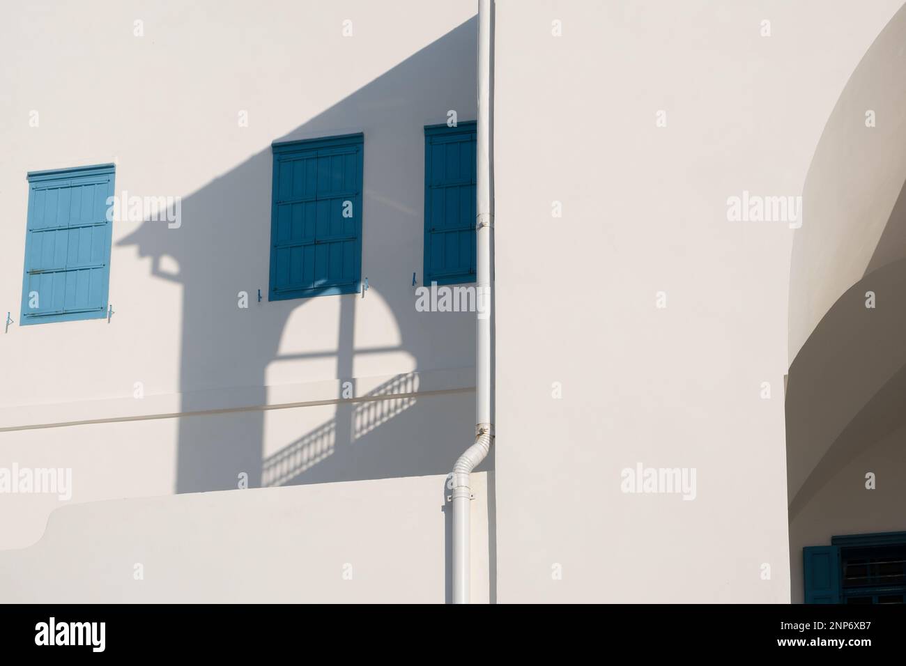 white painted walls and blue windows with shadows on a sunny day ...
