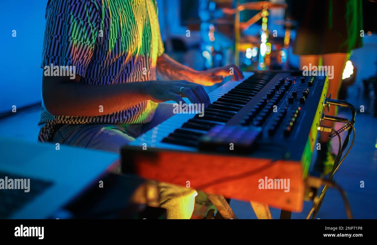 Pianist playing solo part with synthesizer piano on rock concert. Hands ...