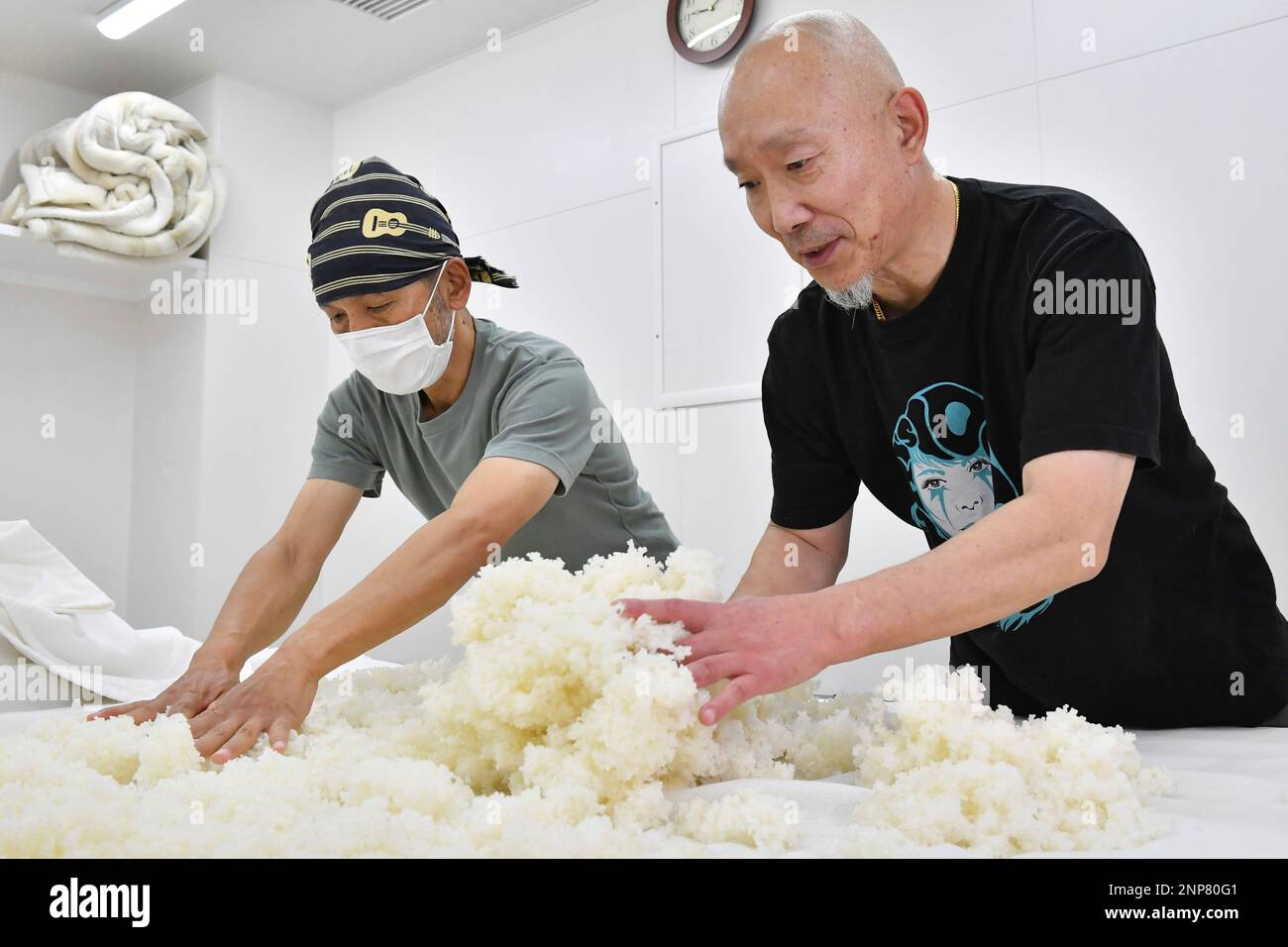 Craftsmen make sake (Japanese rice wine) by mixing steamed rice with ...