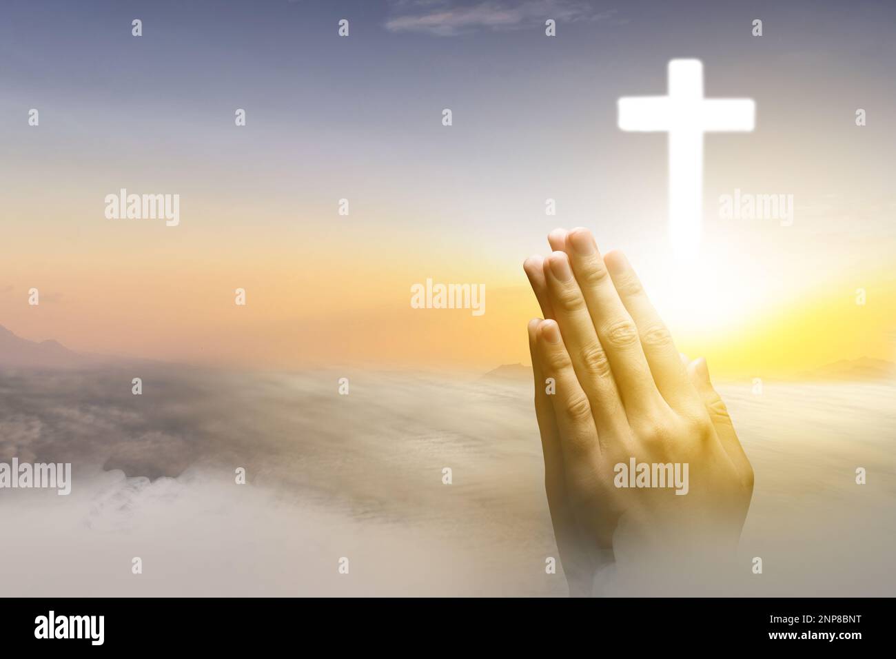 Human hand praying with Christian cross with sunset sky background ...
