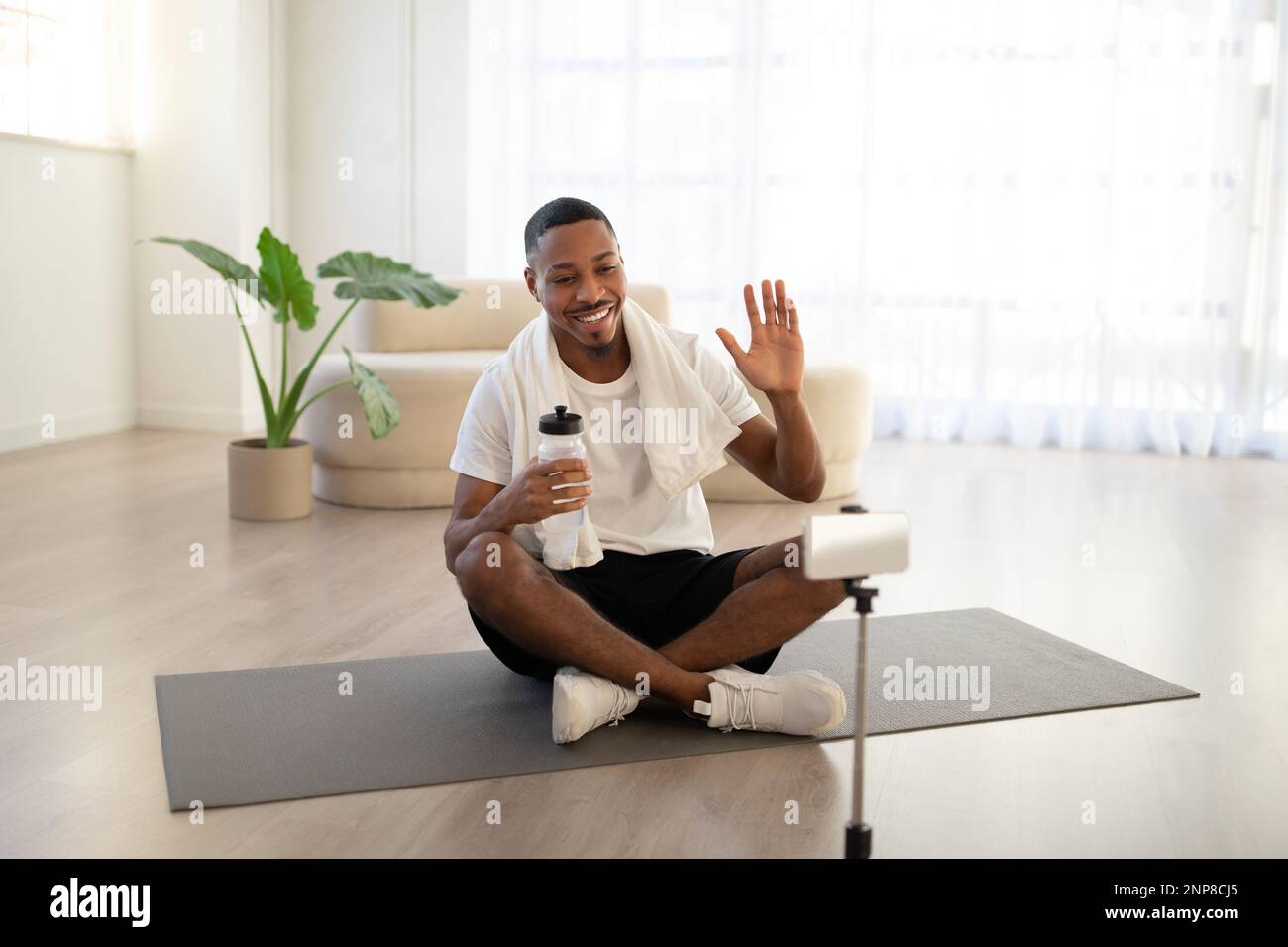 Young black man fitness instructor broadcasting while exercising at ...