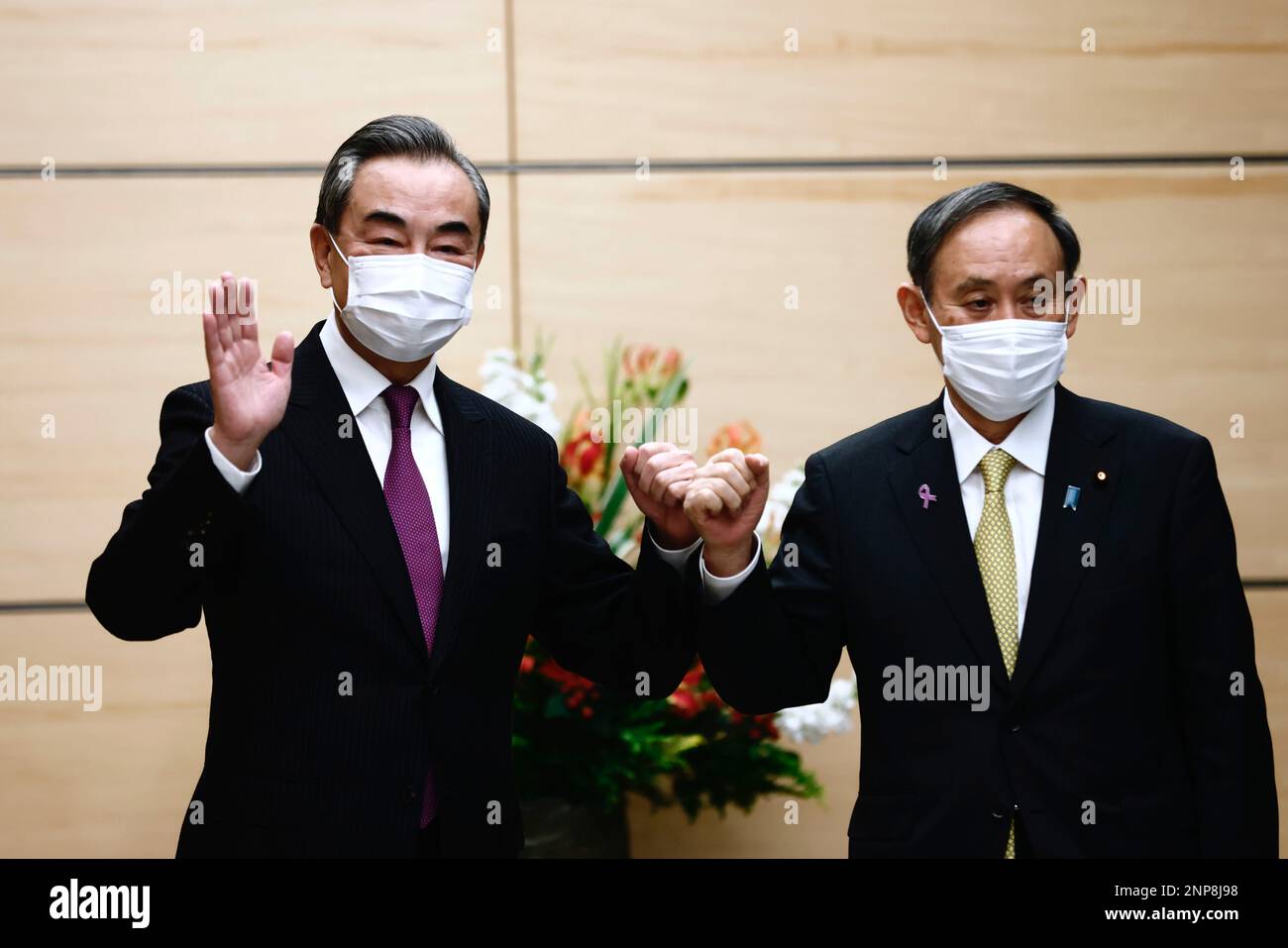 Japan's Prime Minister Yoshihide Suga, right, bumps fists with China's ...