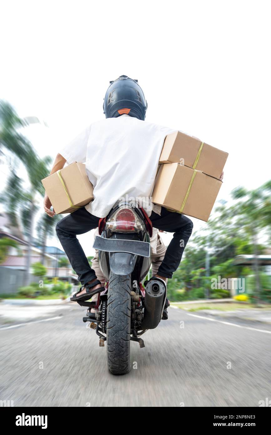 Rear view of Asian Muslim family carrying a box on a motorcycle going ...