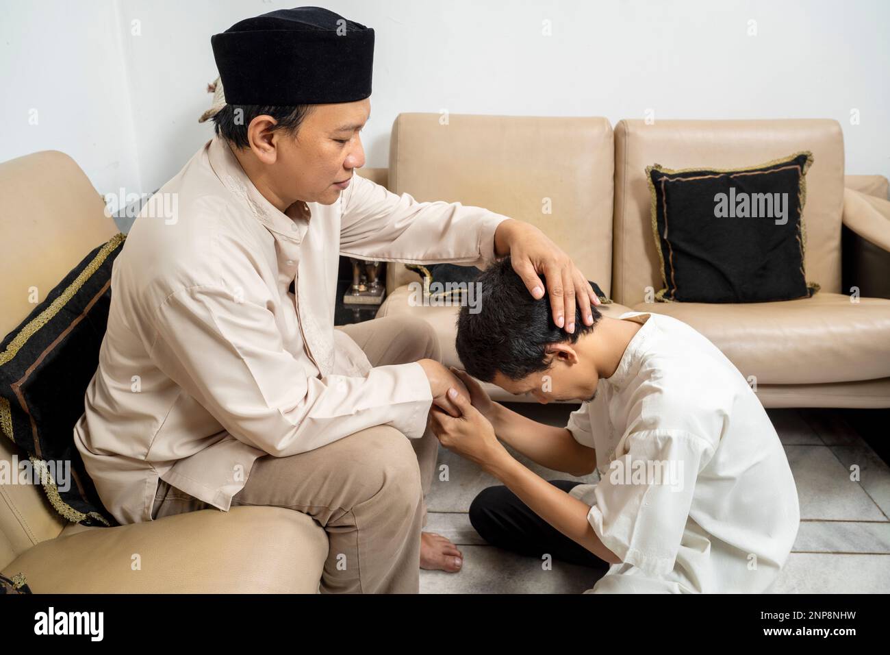 Asian Muslim man asking forgiveness from his father at home. Sungkem is an Indonesian ...