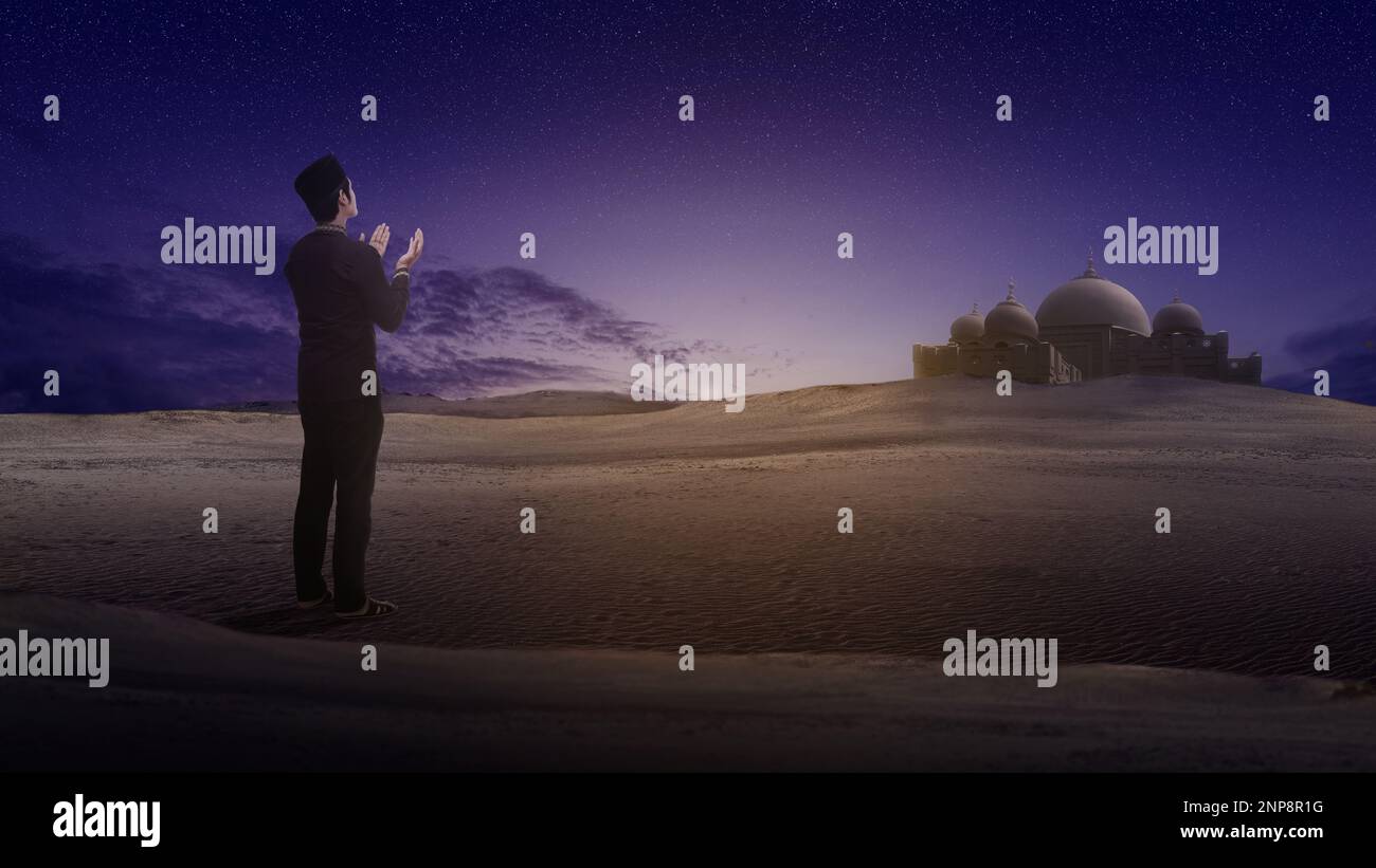Muslim man standing while raised hands and praying with mosque ...