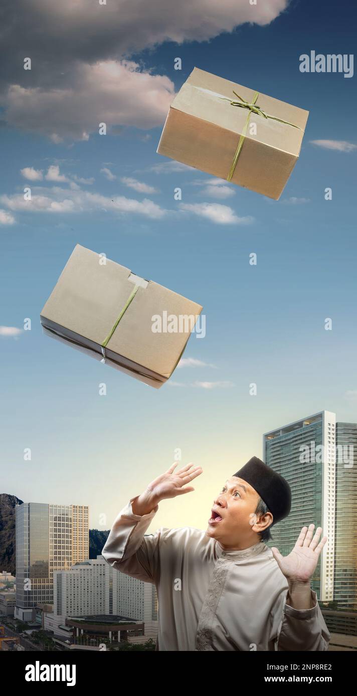 Asian Muslim man afraid of dropping box with blue sky background Stock ...