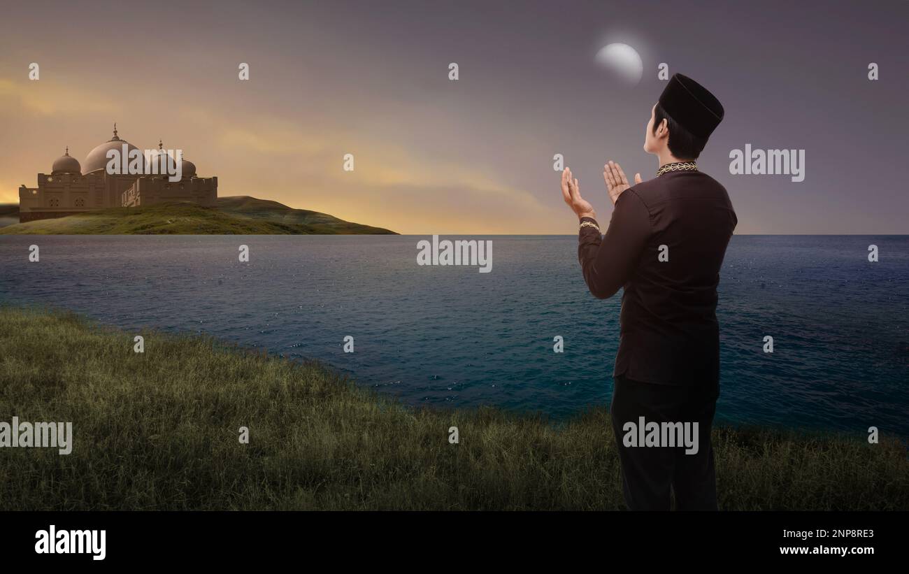 Muslim man standing while raised hands and praying with mosque ...