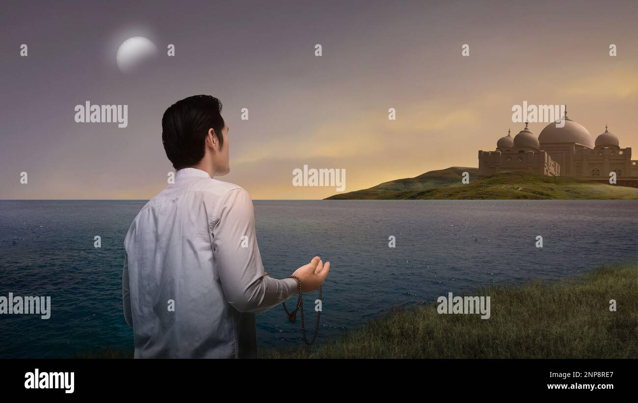 Muslim man standing while raised hands holding prayer beads and praying ...