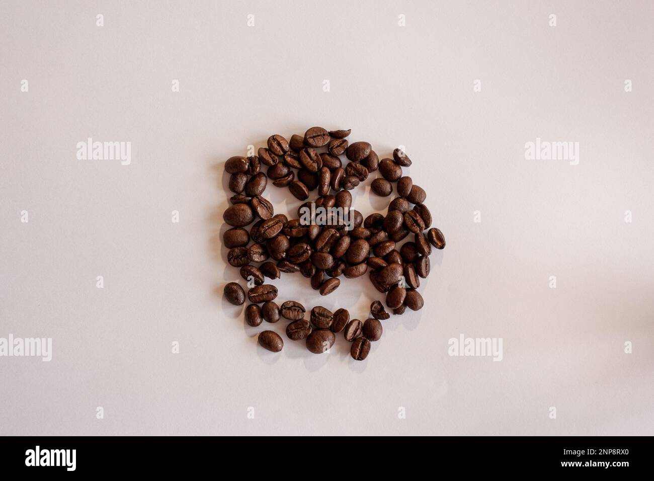 Coffee beans form a face in negative, eyes and mouth are white. The ...