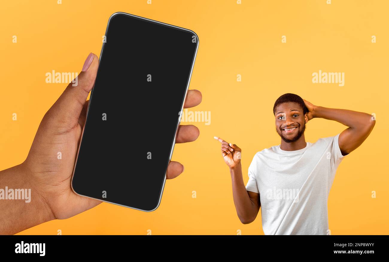 Happy Black Guy Pointing At Big Blank Smartphone In Huge Female Hand ...