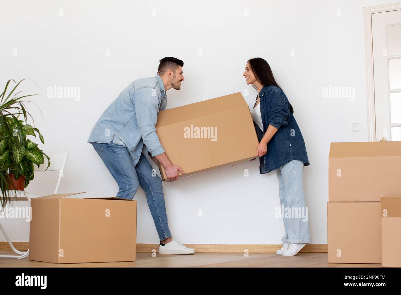 Happy Young Couple Carrying Big Cardboard Box With Bellongings At Home ...