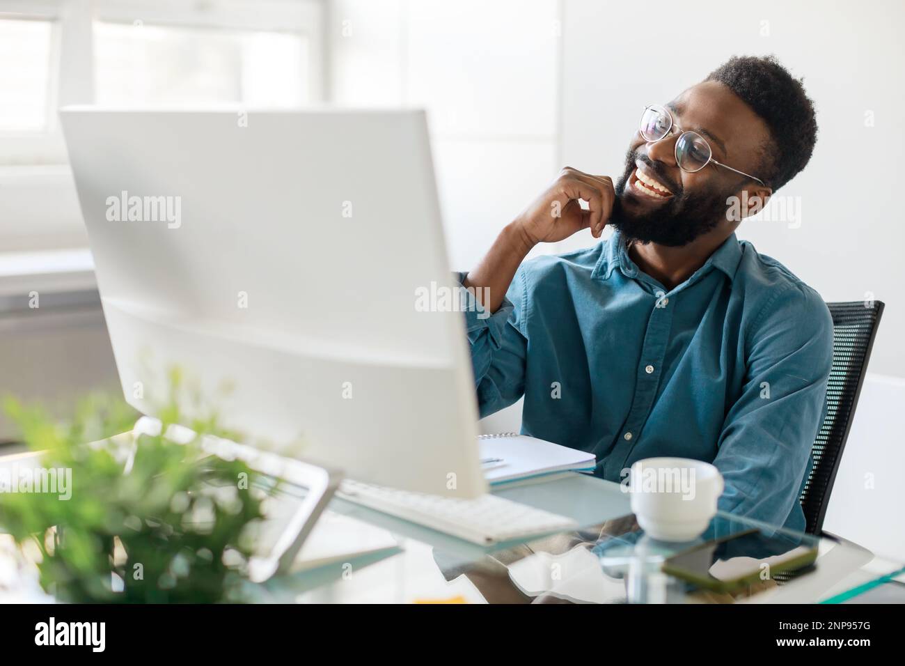 Happy black male manager sitting at office desk in front of computer ...