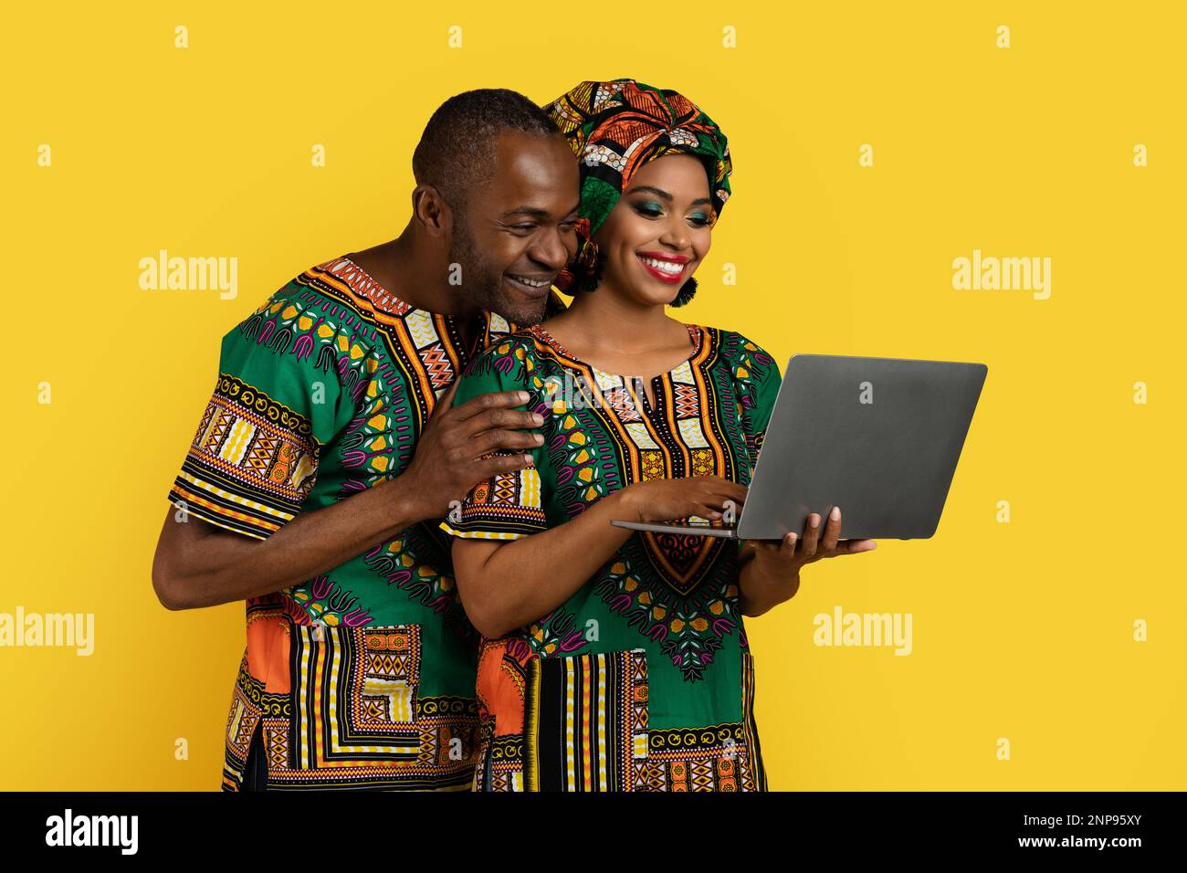 Beautiful black couple using modern laptop on yellow Stock Photo - Alamy