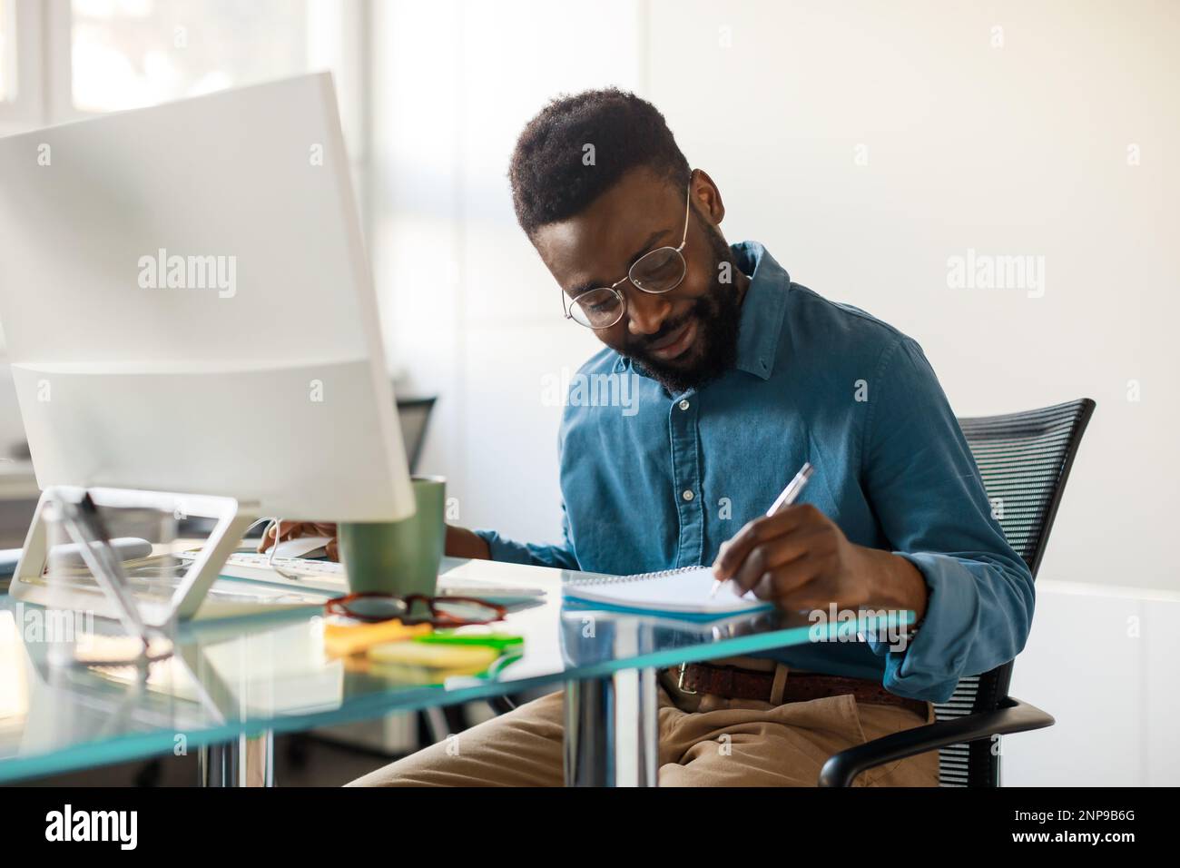 Happy black executive ceo manager using laptop and writing notes in ...