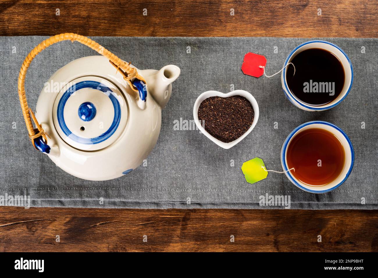 Porcelain teapot next to a small heart-shaped bowl with ground tea, two ...