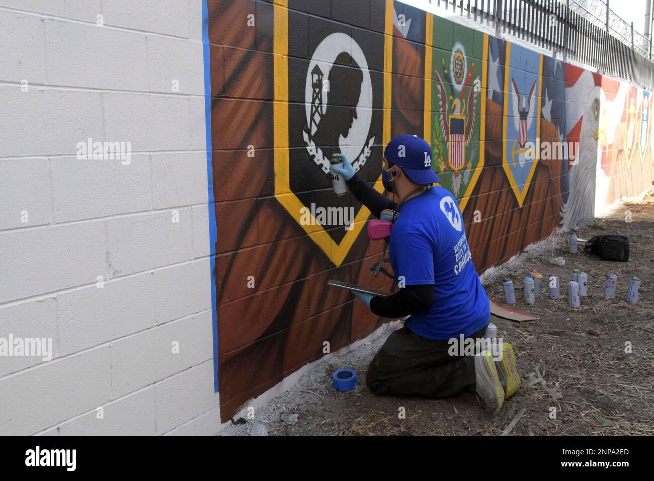 A volunteer paints a mural at the MLB All-Star Veterans Courtyard ...