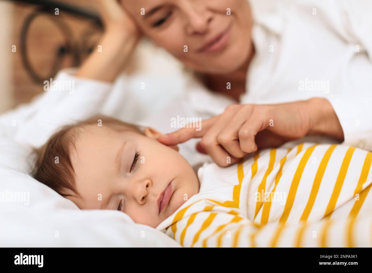 Young woman caressing her sleeping little baby girl, woman touching her ...