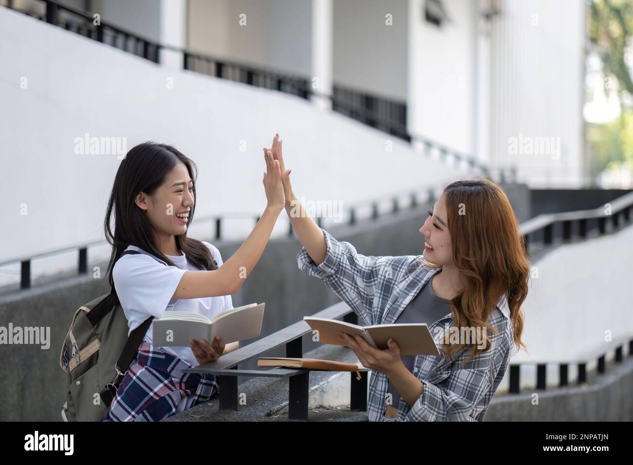 Cheerful Asian college two female students are talking, sharing ideas ...