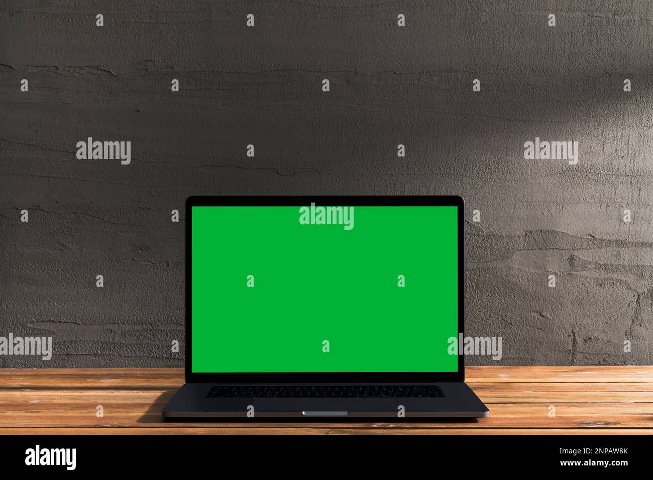 Chroma key green screen laptop on wooden table in front of concrete ...