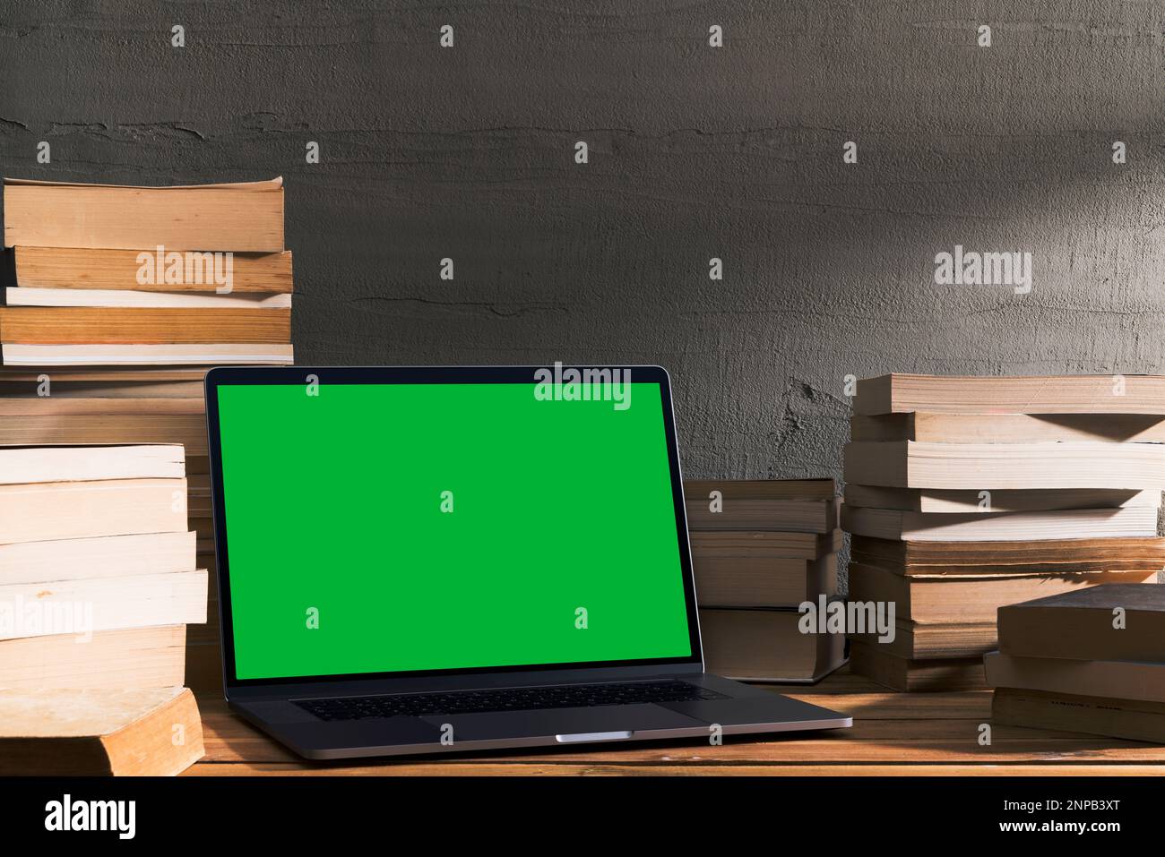 Chroma key green screen laptop with pile of books on wooden table in ...