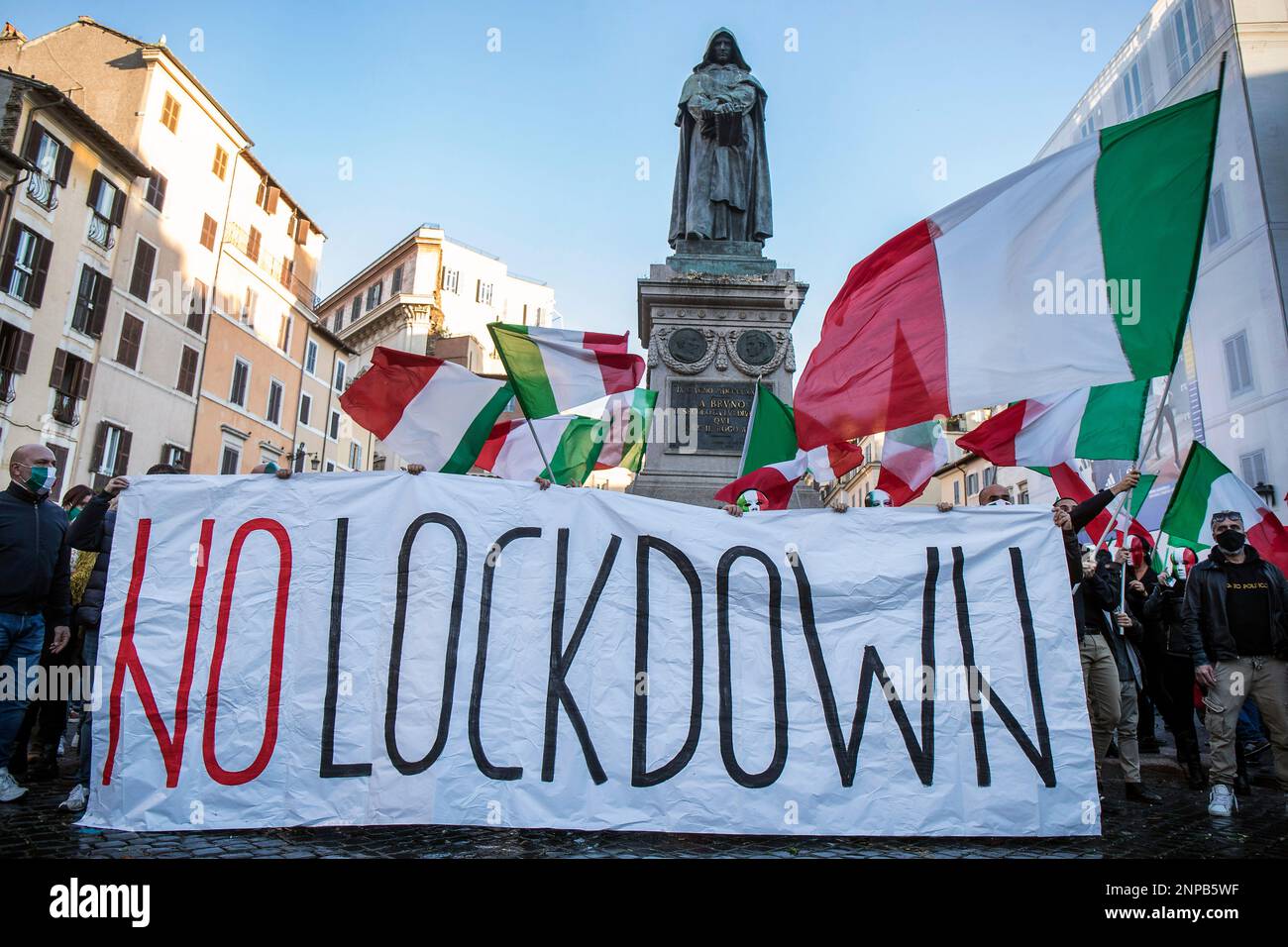 Demonstrators wearing masks with the colors of the Italian flag wave ...