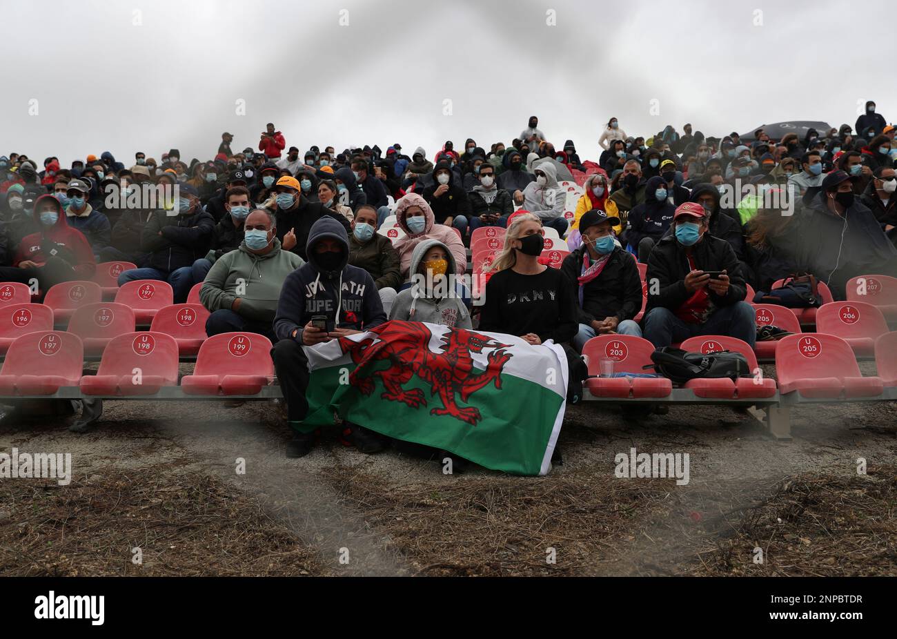 Fans sit behind a fence as they watch the Formula One Portuguese Grand ...