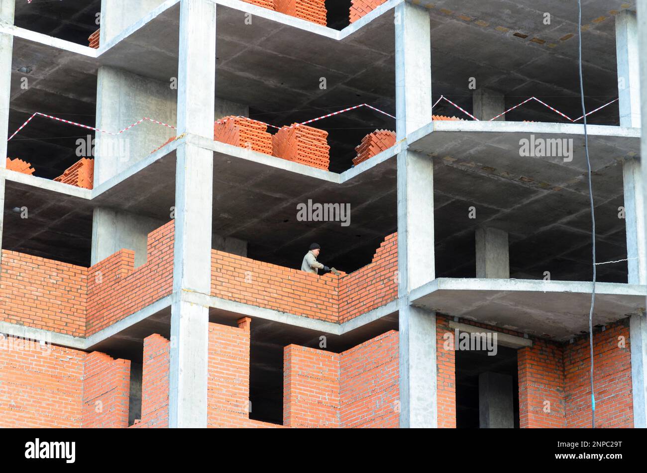 Two builders lay brick walls in a multi-apartment new house under ...