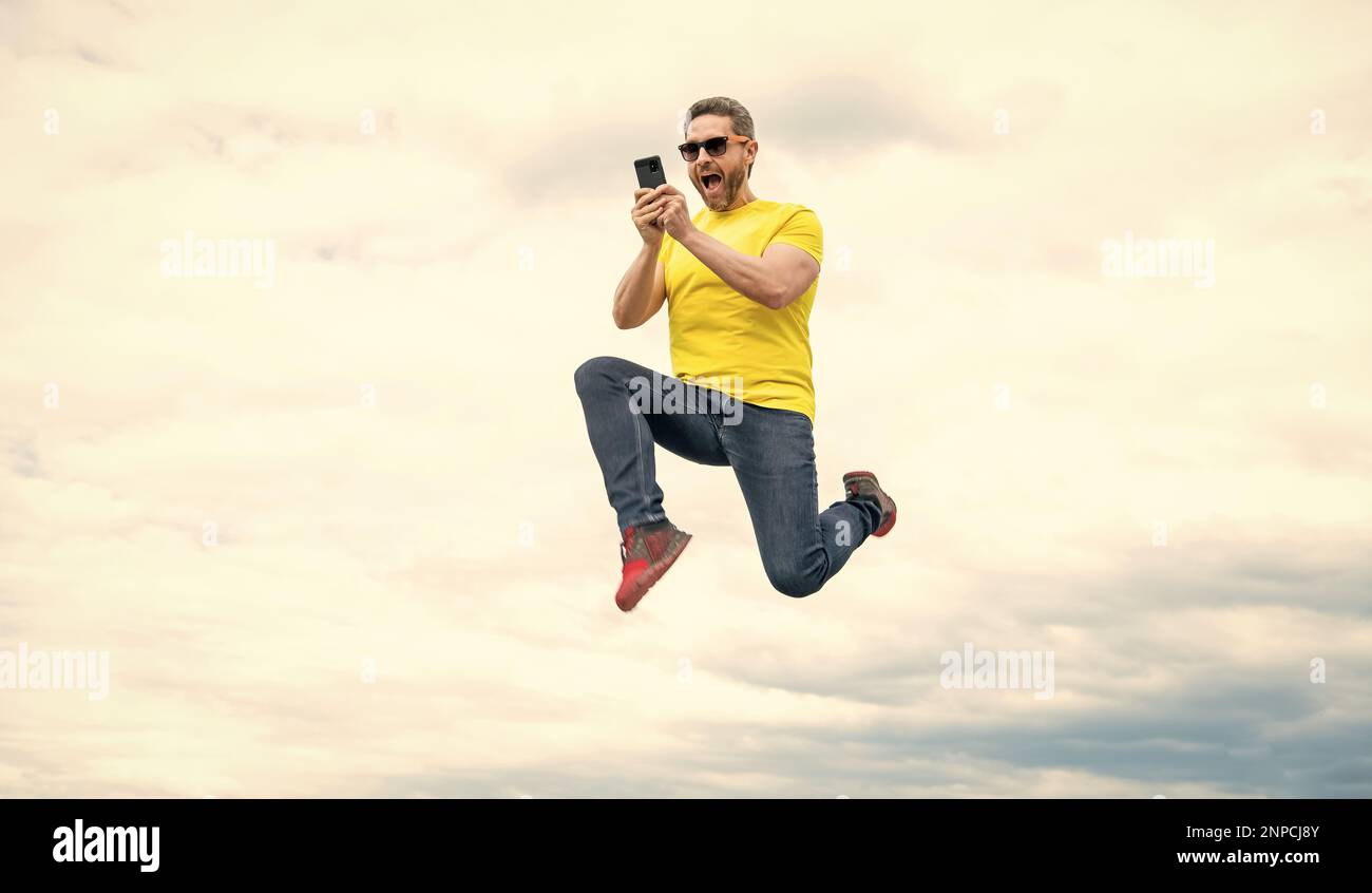 man jumping and chatting on phone on sky background Stock Photo - Alamy