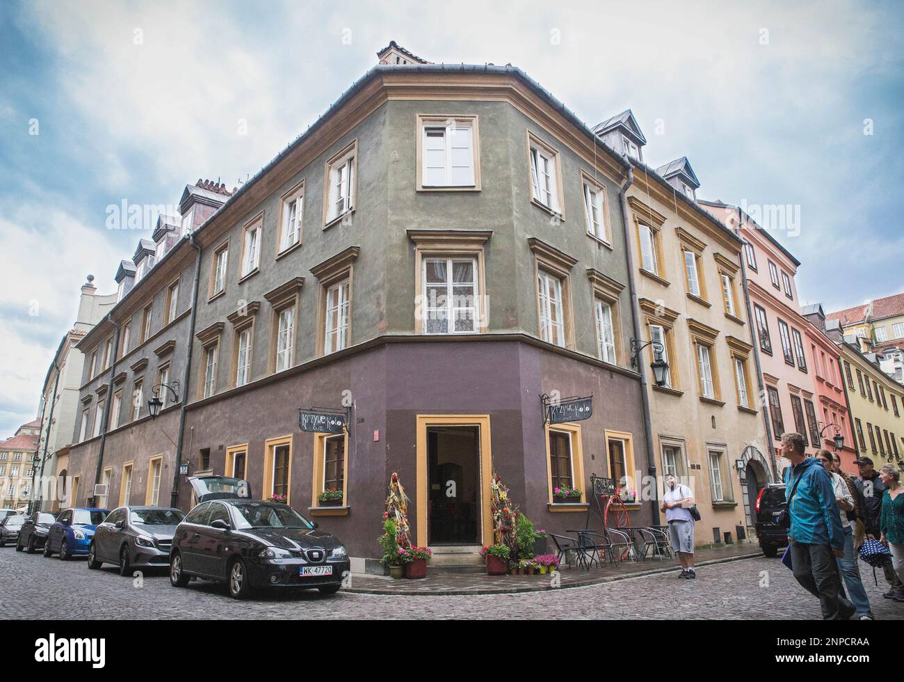 Beautiful corner house in Warsaw. Tourists walk the cobbled streets ...