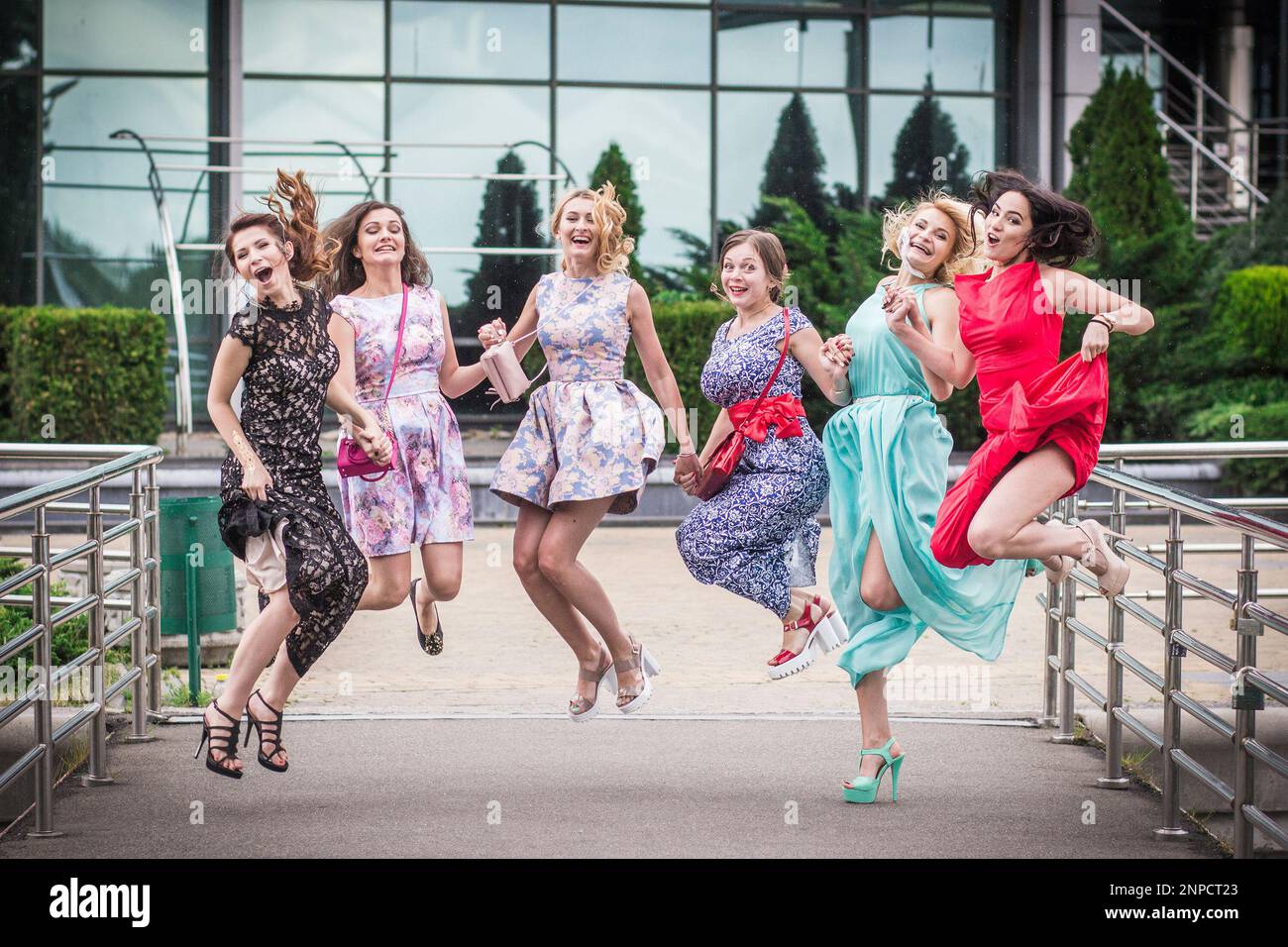 Beautiful girls university graduates jumping with happiness under rain ...