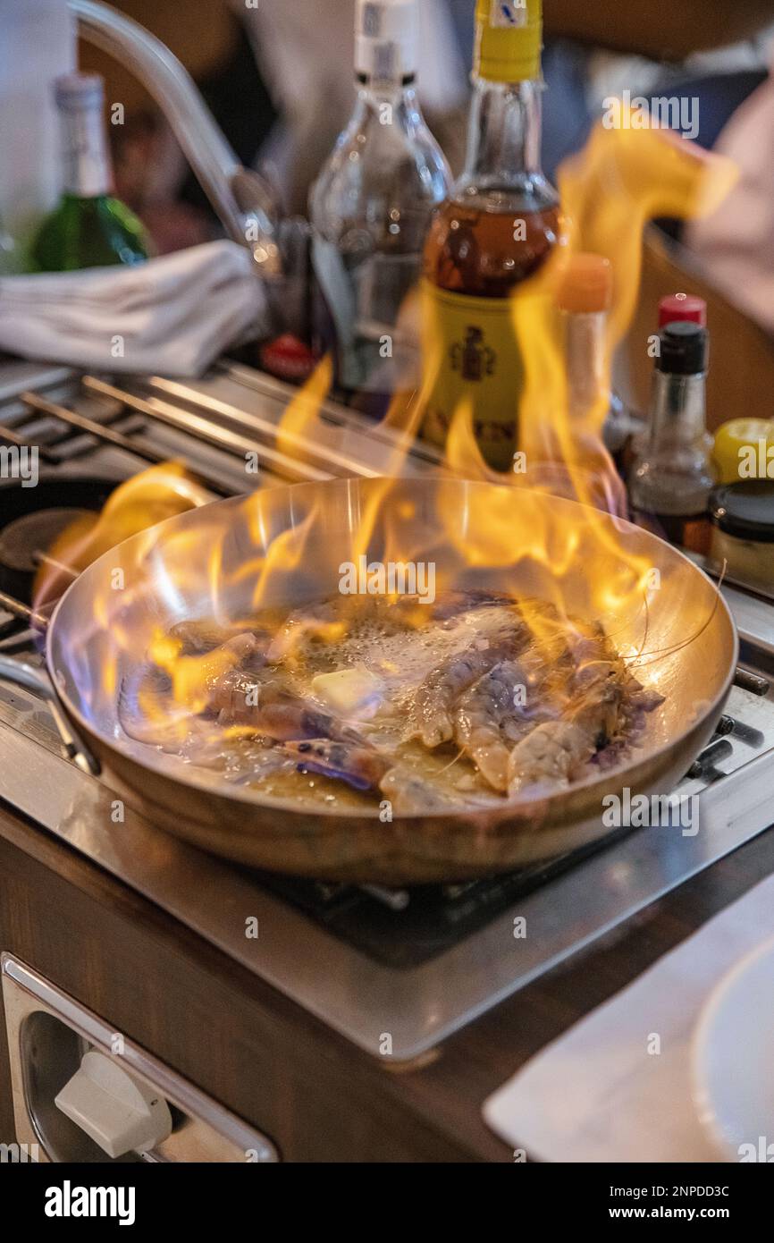 Delicious flambeed dish with large king prawns covered by large flames ...