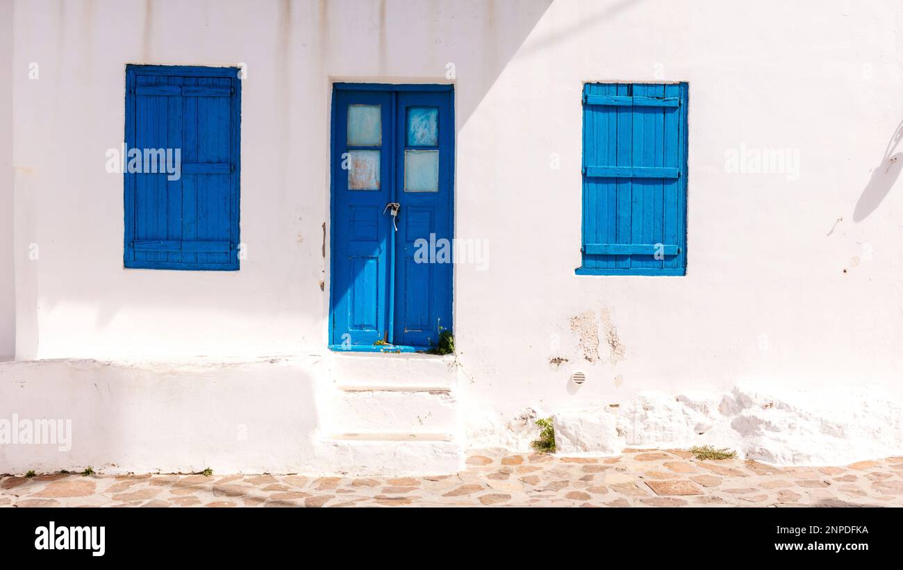 A close up view of a whitewashed building with blue doors and windows ...