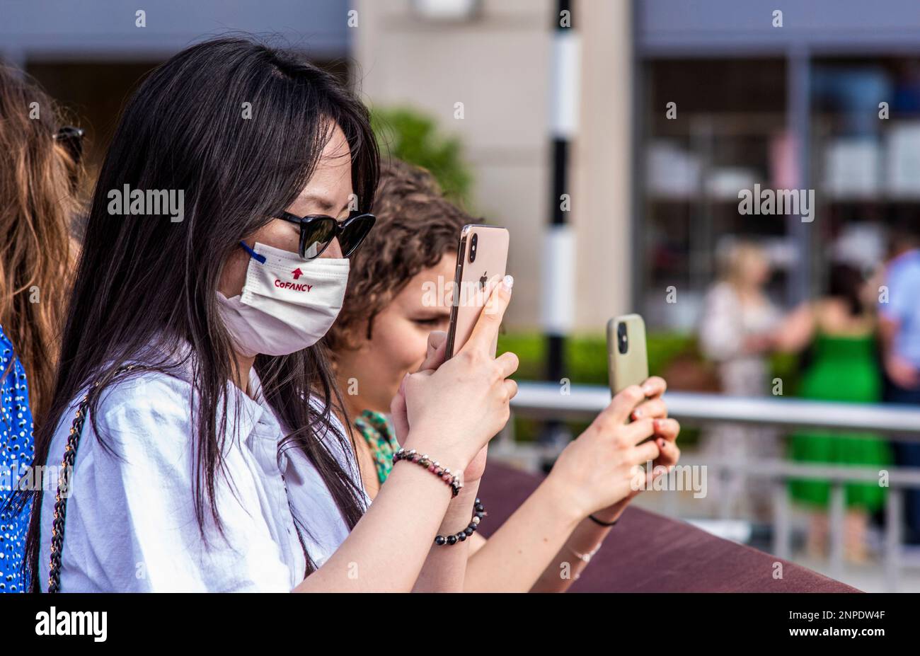 Two young ladies take pictures with their smart phones with the one in ...