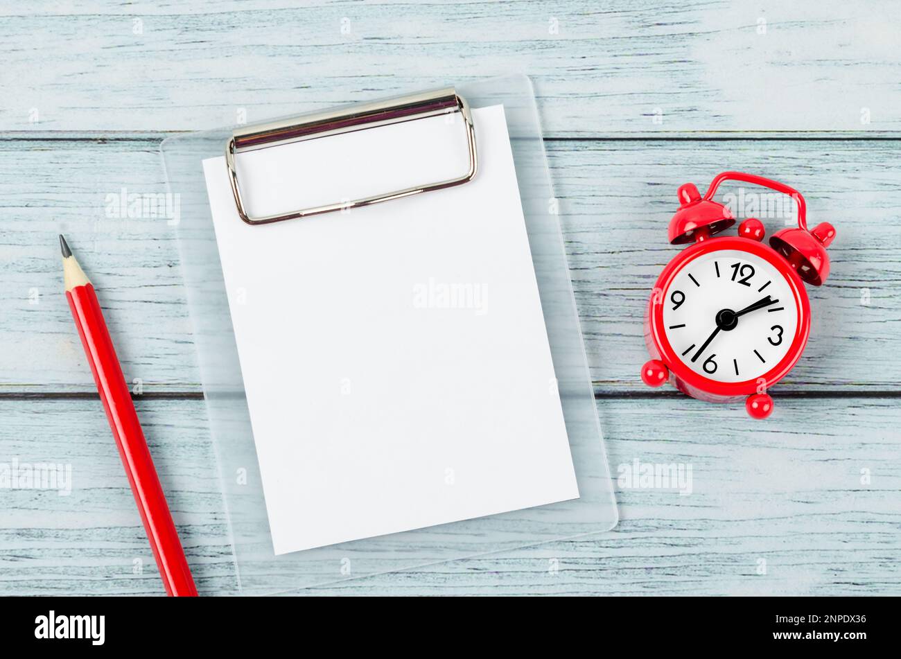 Small white paper blank page on clip board, alarm clock and wooden ...