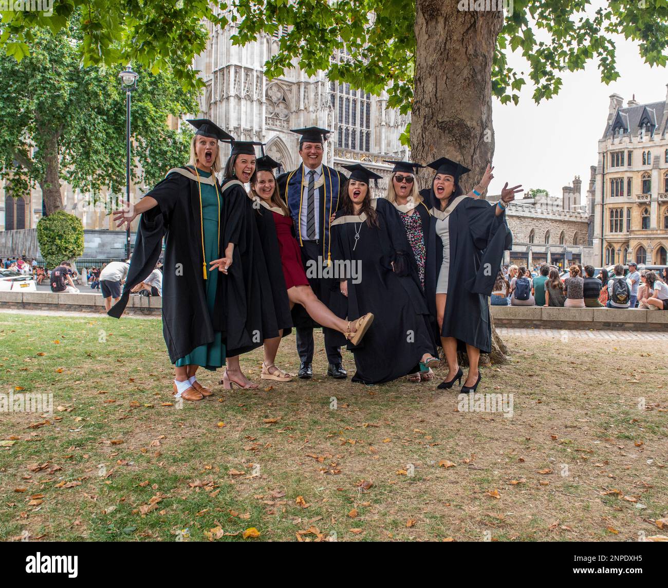 A group of graduates pose for a photograph on a scorched brown patch of ...