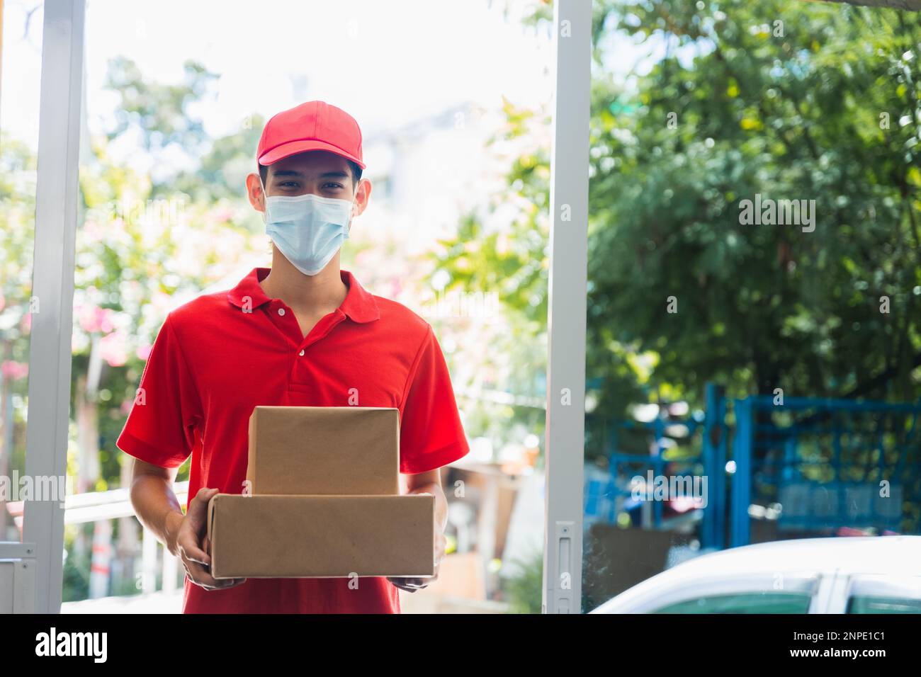 Asian delivery man wearing face mask in red uniform deliver service ...
